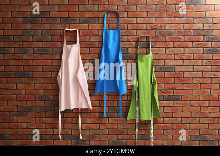 Many chef's aprons hanging on brick wall Stock Photo - Alamy