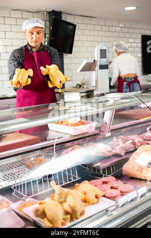 Adult butcher showing fresh gutted chickens in butchery Stock Photo - Alamy