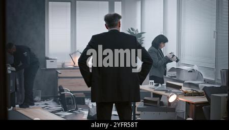 Office robbery case: Back view of detective examining crime scene ...