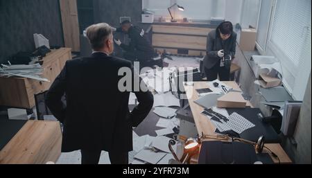 Office robbery case: High angle of detective examining crime scene ...