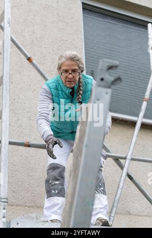 Gerüstbauerin, Malerin baut ein mobiles Gerüst am Einfamilienhaus auf ...