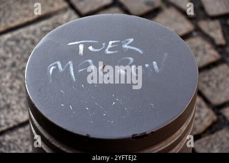 View of an Anti-parking bollard with inscription "Tuer Macron". Tag ...