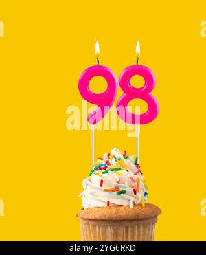 Pink number 98 birthday candle lit on white background Stock Photo - Alamy