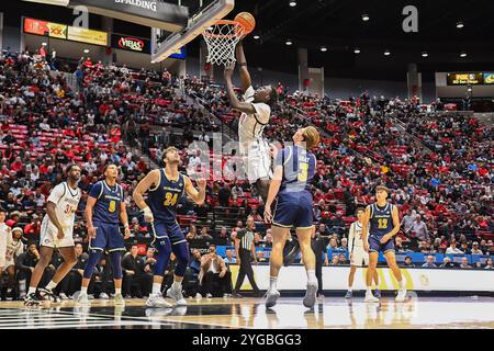 San Diego State forward Magoon Gwath (0) dunks as Utah State guard Ian Martinez (4) looks on ...