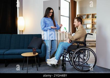 Man in wheelchair extend her hand palm up to side. Woman giving key ...