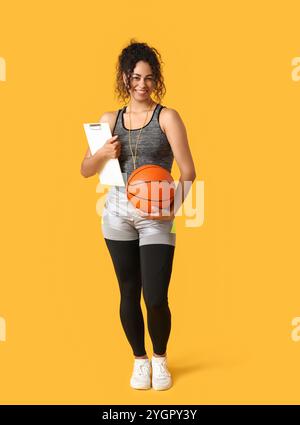 Female African-American basketball trainer with ball and gold cup on ...