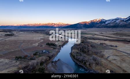 Aerial view of a bending river flowing and crossing wide green field ...