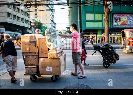 A Filipino market worker pulls his trolley along the street in a market ...
