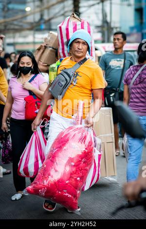 A Filipino market worker carries his goods along the street in a market ...