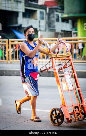 A Filipino market worker pushes his trolley along the street in a ...
