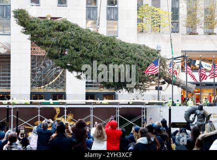 Spectators watch as workers lift into place by crane the Rockefeller ...