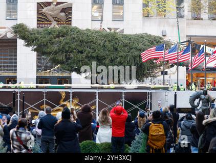 Spectators watch as workers lift into place by crane the Rockefeller ...