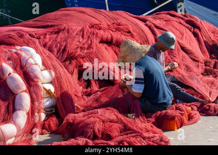 Fishermen weaving nets by the sea Stock Photo - Alamy