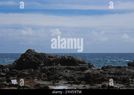 Rocky shoreline with rugged boulders stretching into the sea, waves ...