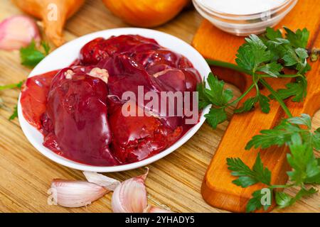 Picture of raw chicken liver with garlic and greens on wooden surface ...