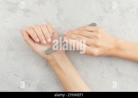 Woman filing damaged nails. Fingernails with onycholysis after removing ...