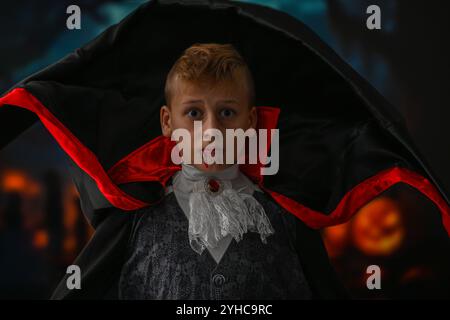 Child dressed as a vampire posing in front of a blurred background with ...