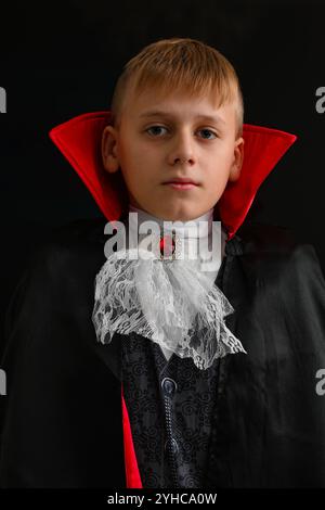 Portrait of a boy wearing a vampire costume posing on a black ...