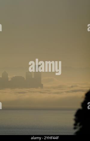 The Seattle skyline seen at sunrise rising above a low golden fog ...