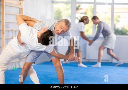Man practices hip flip technique with his sparring partner during group ...