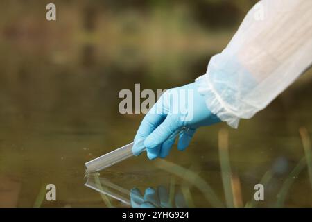 Examination of water quality. Researcher taking water sample from lake ...