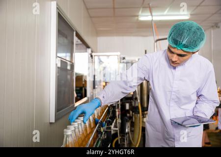 Quality control officer inspects beverage bottling factory line with ...