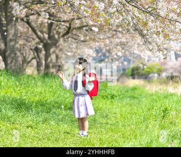 First grade girl waving under the cherry tree Stock Photo - Alamy