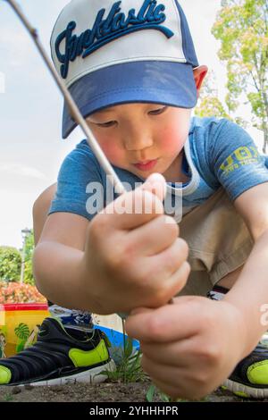 Cute boy digging soil in forest near sea beach. Family natural ...