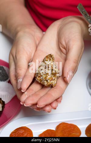 Woman makes candies from dried fruits. Balls of prunes, dates and ...
