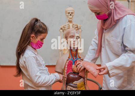 A Muslim female teacher uses the human body model to explain anatomy in ...