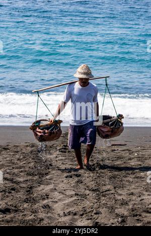 Man gathering sea water to produce sea salt in Amuk Bay, Eastern Bali ...