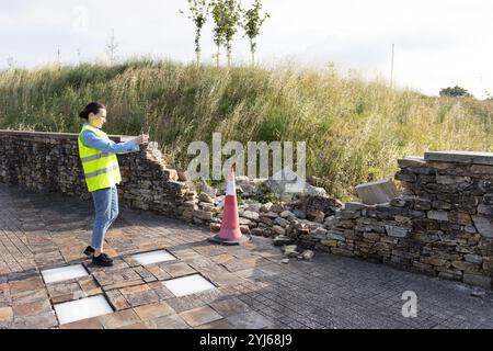 Insurance claims adjuster taking a photo with her tablet to a damaged ...