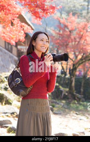 Woman taking photos of autumn leaves with a camera Stock Photo - Alamy