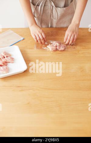 A woman is wrapping meat in plastic wrap. Concept of preparation and ...