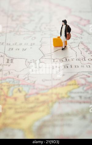 Miniature woman holding suitcase on world map Stock Photo - Alamy