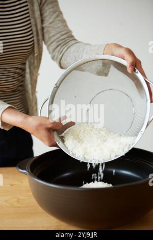White rice, earthenware pot and woman's hand Stock Photo - Alamy