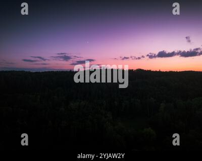 Colorful sunset over forest treeline Stock Photo - Alamy