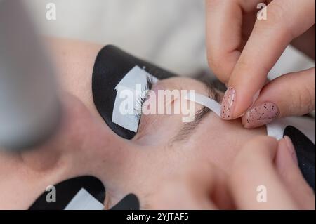 A specialist glues a client's drooping eyelid before eyelash extensions ...
