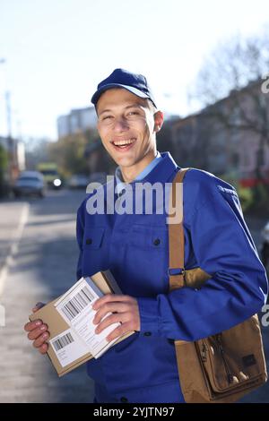 Happy postman with parcels outdoors. Mail service Stock Photo - Alamy