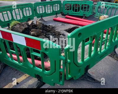 road excavation surrounded by green safety barriers and tools ...