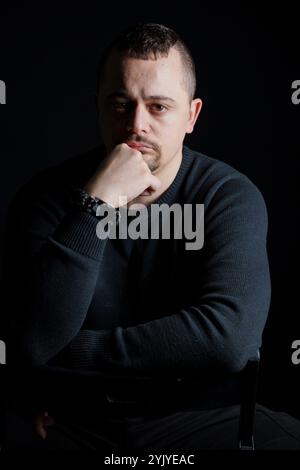 Introspective Man Seated in Dramatic Lighting Against Dark Background ...