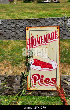 An old enamelled metal tin sign advertising a cold beer on a fence in ...