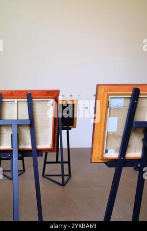 Wooden easels at a museum art exhibit seen from behind; rear view of ...