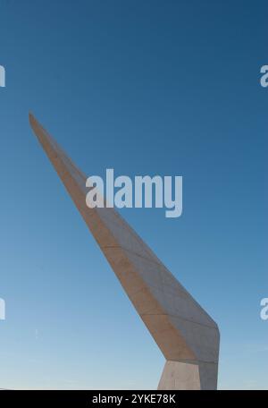 A striking white concrete monument standing tall against sunset sky ...