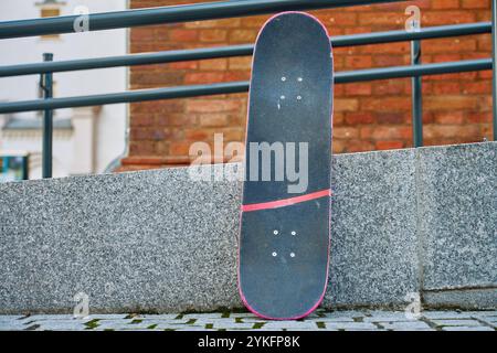 Used scratched pink skateboard against stone wall at city street. Urban ...