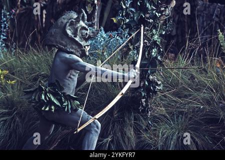 Asaro warrior, also known as Holosa, in clay mud man mask with bow and ...