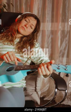 Portrait of young woman relaxing with ukulele guitar on the bridge in ...