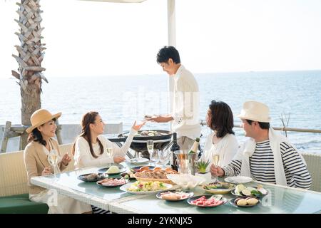 Five men and women barbecuing at a restaurant on the beach Stock Photo ...