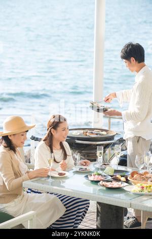 Family barbecuing at a restaurant on the beach Stock Photo - Alamy