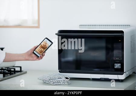 Women's hands, microwave and smartphone Stock Photo - Alamy